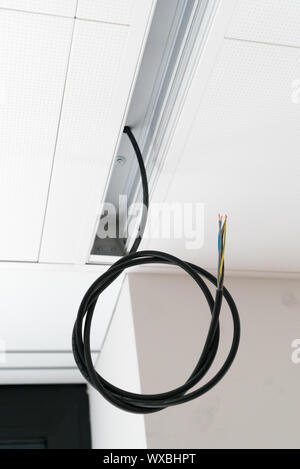 Cables are hanging from ceiling of building under construction, work in ...