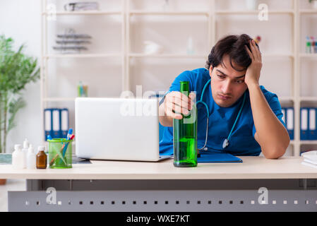 Young male doctor drinking in the office Stock Photo - Alamy