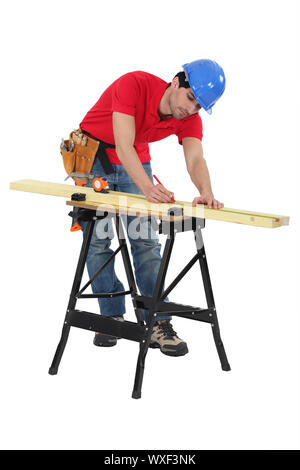 Handsome carpenter working with a wood, marking plank with a pencil in ...