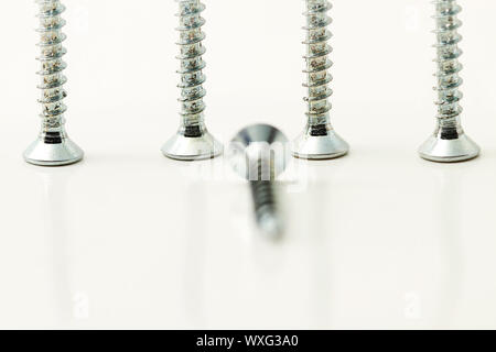 four screws standing behind one screw on white background Stock Photo ...