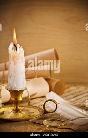 Vintage paper rolls feather candlestick candle on wooden board Stock ...