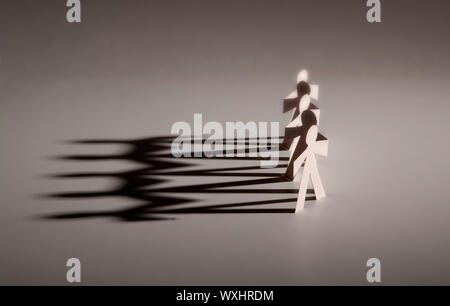 Line of cutout paper dolls throwing a shadow Stock Photo - Alamy