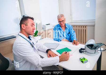 Serious middle aged doctor prescribes his senior patient the medication ...