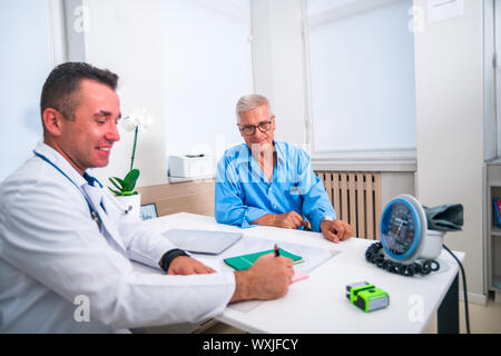 Serious middle aged doctor prescribes his senior patient the medication ...