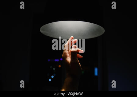 Man's hand reaching towards a ceiling light Stock Photo - Alamy