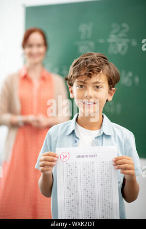 Happy boy with answer sheet for school test on white background Stock ...