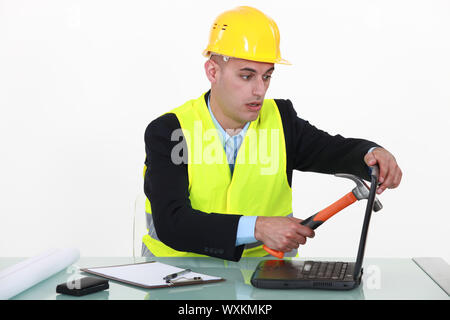 Builder smashing laptop screen Stock Photo - Alamy
