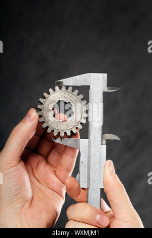 Man measuring the diameter of old cog with vernier caliper. Lots of ...