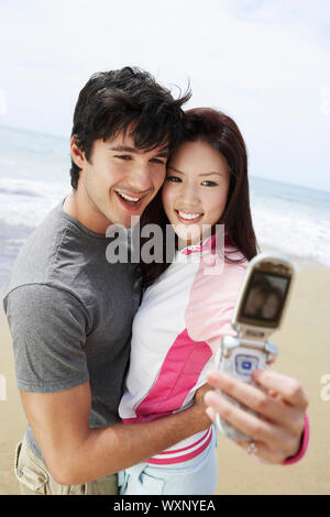 Diverse boyfriend and girlfriend hugging and taking selfie via ...
