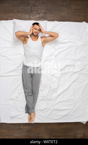 A Caucasian man feeling sick while holding a medicine and lying on the ...