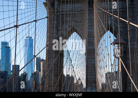 Skyscrapers of Manhattan viewed through wire supports and cables of ...