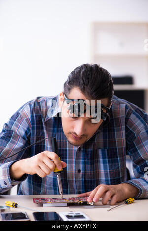 The young handsome technician repairing mobile phone Stock Photo - Alamy