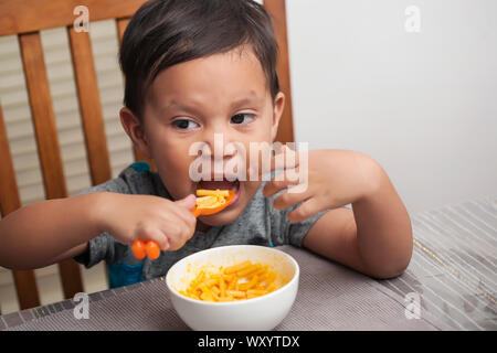 Child eating independently with a spoon, feeding himself, making a mess ...