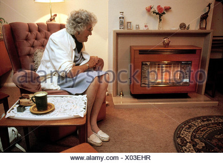 old woman sitting by gas fire Stock Photo - Alamy