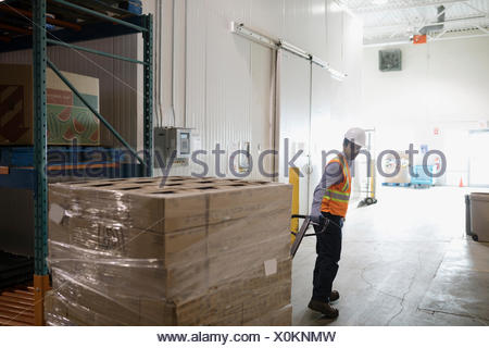 Worker in protective workwear pulling pallet truck in factory Stock ...