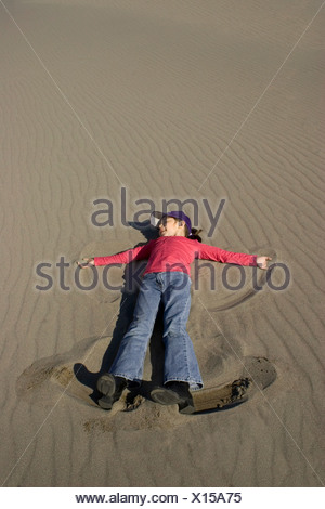 Girl making angel in sand on beach, high angle view Stock Photo - Alamy