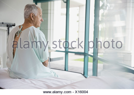 Patient sitting on hospital bed wearing hospital gown Stock Photo ...