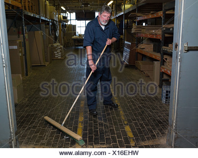 Man sweeping warehouse floor with broom Stock Photo: 50015394 - Alamy