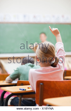 Child putting her hand up to answer a question at school Stock Photo ...