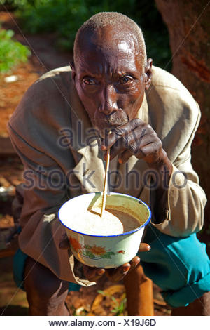man drinking traditional banana beer 'pombe' with drinking straw ...