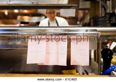 Cook and detail of restaurant order ticket slips in kitchen Stock Photo ...