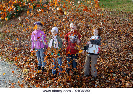 four kids playing in Fall leaf pile Stock Photo - Alamy