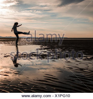 Woman kicking water on the beach Stock Photo - Alamy