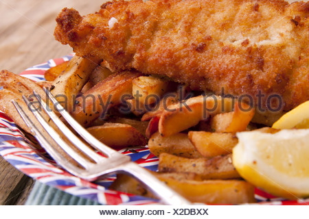 Traditional British takeaway meal of battered fish and chips, plus ...