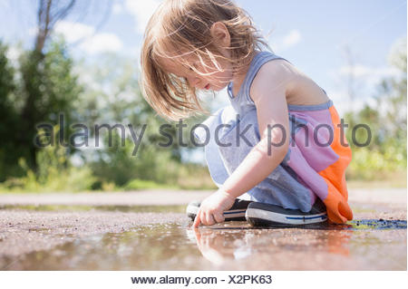Girl looking at her reflection in a puddle of water in the street Stock ...