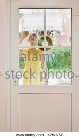young girl knocking on front door of house using metal door knocker ...