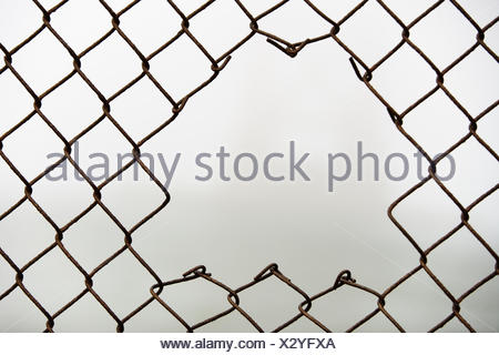 Broken and damaged chain link fence with orange background Stock Photo ...