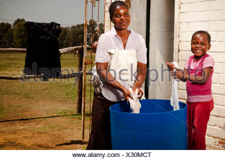 African girl washing laundry by hand in brightly coloured buckets Stock ...