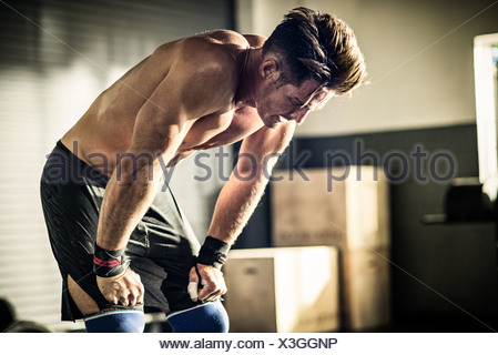 Young man bending forward with exhaustion in gymnasium Stock Photo ...
