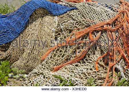 A pile of old fishing nets made of natural fibre and blue synthetic ...
