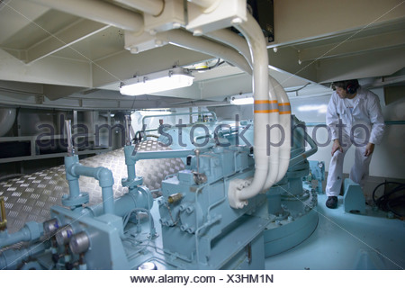 Marine engineer working in ship's workshop in engine control room ECR ...