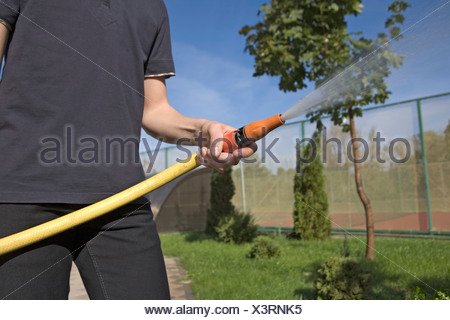 Teenage boy spraying water hose Stock Photo: 51456630 - Alamy