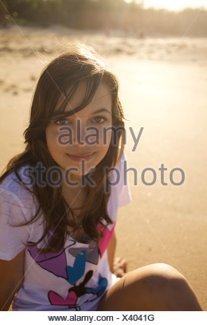 A pre-teen girl at Paia Beach, Maui, Hawaii rests on her surf board ...