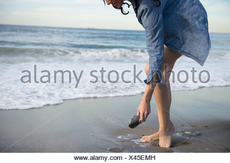 A woman collecting seashells on the beach Stock Photo - Alamy