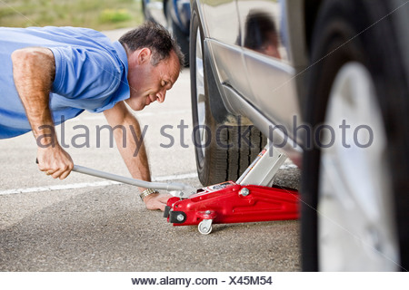 Man jacking up a vehicle Stock Photo: 23681281 - Alamy