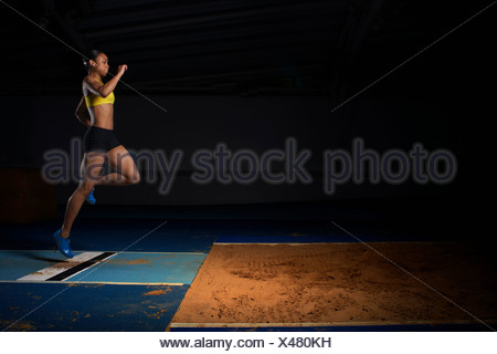 Woman doing long jump Stock Photo - Alamy