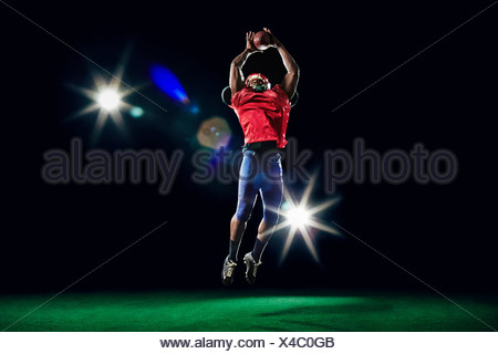 American football player catching ball mid air in stadium Stock Photo ...