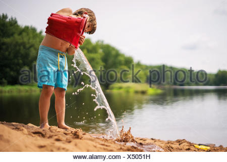 Boy pouring bucket of water on himself Stock Photo: 52350395 - Alamy
