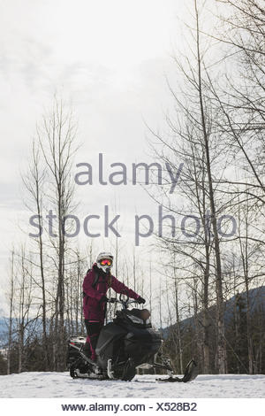 Woman riding snowmobile in snowy alps during winter Stock Photo ...