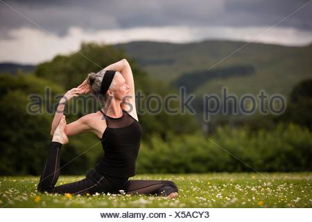 Mature woman doing splits practicing yoga position in field Stock Photo ...