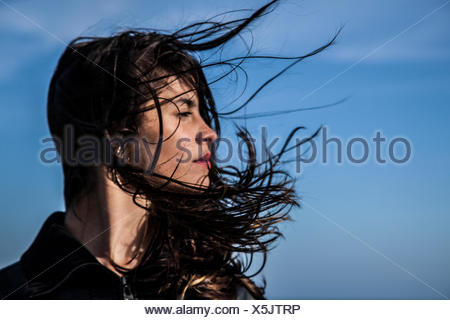 Young woman looking sideways with hair blowing in the wind Stock Photo ...