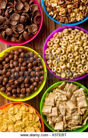 top view of various kids cereals in colorful bowls on wooden table ...