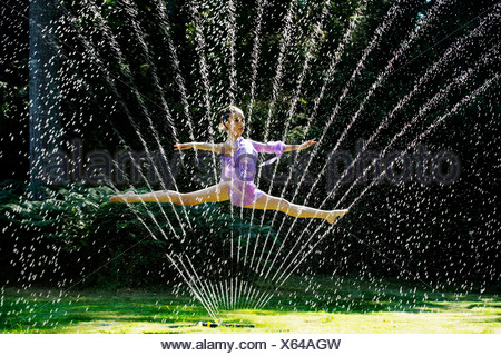 Girl jumping through lawn sprinkler Stock Photo: 29727092 - Alamy