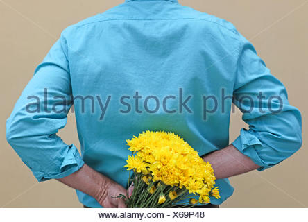 Man holding flower behind his back, rear view Stock Photo - Alamy