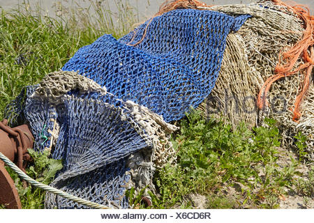 A pile of old fishing nets made of natural fibre and blue synthetic ...