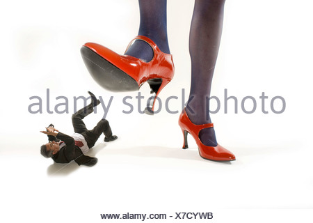 Woman in red high heels stepping on a shrunken man Stock Photo ...